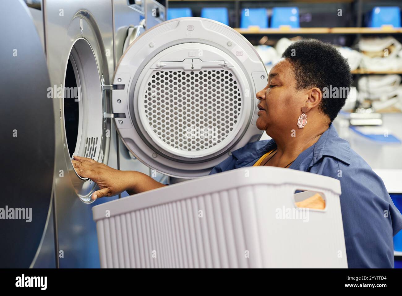 Side view of senior Black woman carefully loading clothes from basket ...