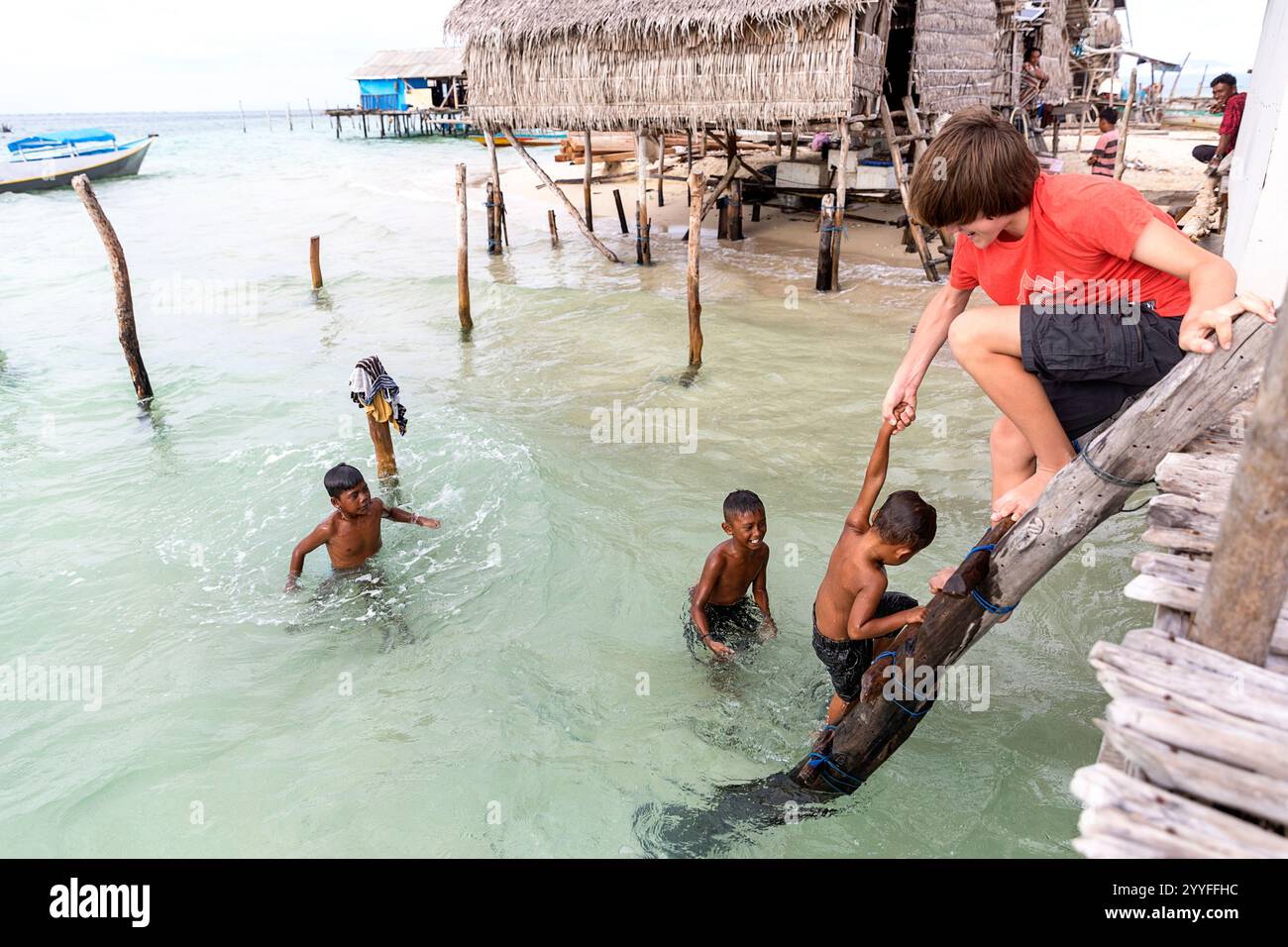 Boys from bajau laut minority jumping in a water in a village in the ...