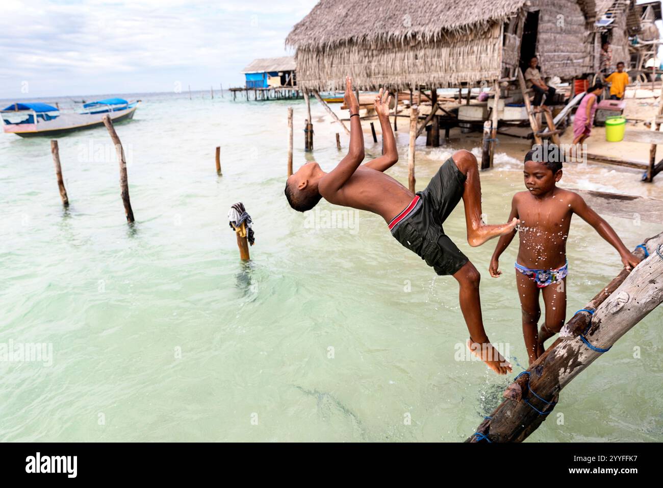 Boys from bajau laut minority jumping in a water in a village in the ...