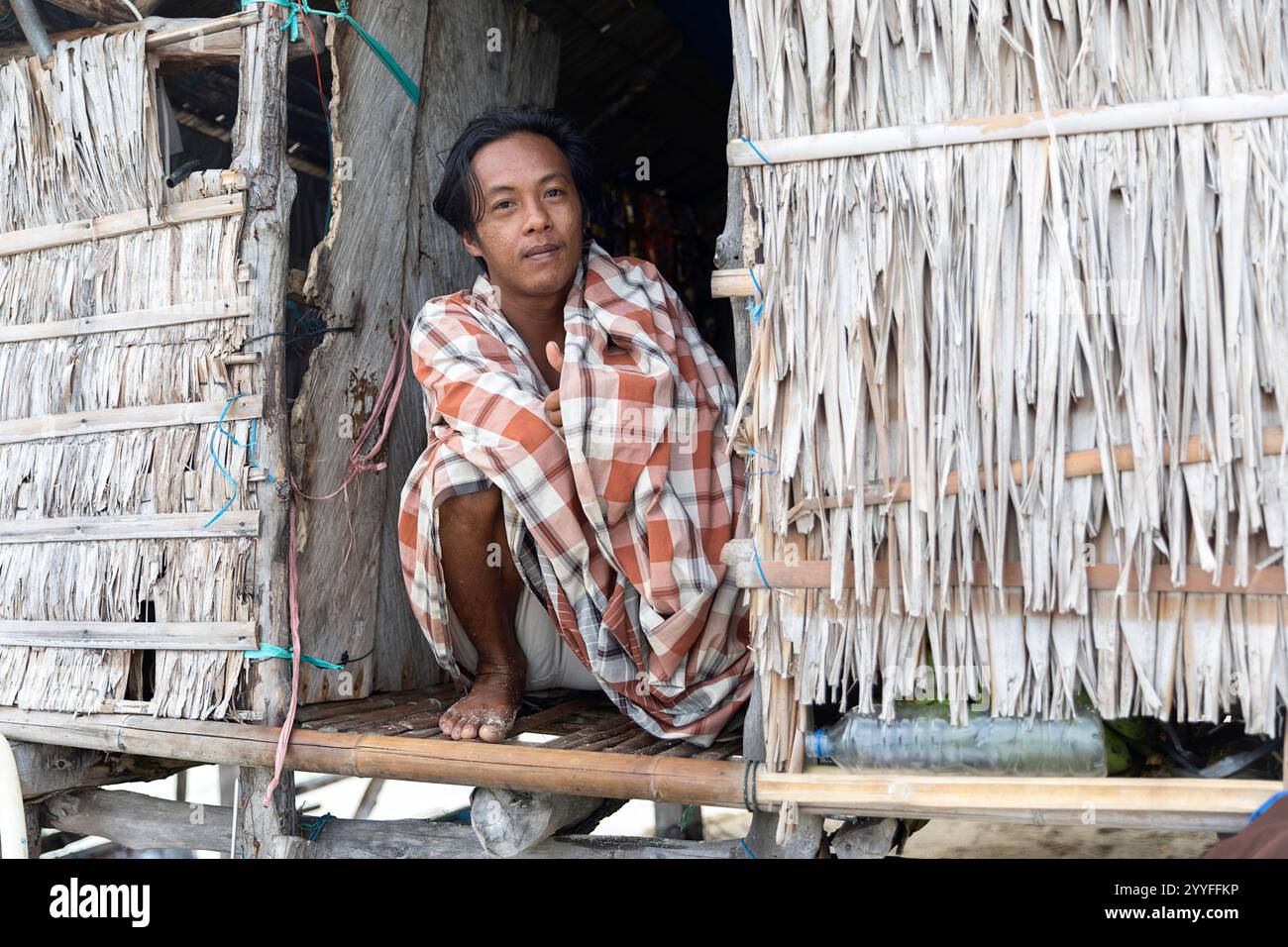Man from Bajau laut minority sitting at the entrance to his wooden ...