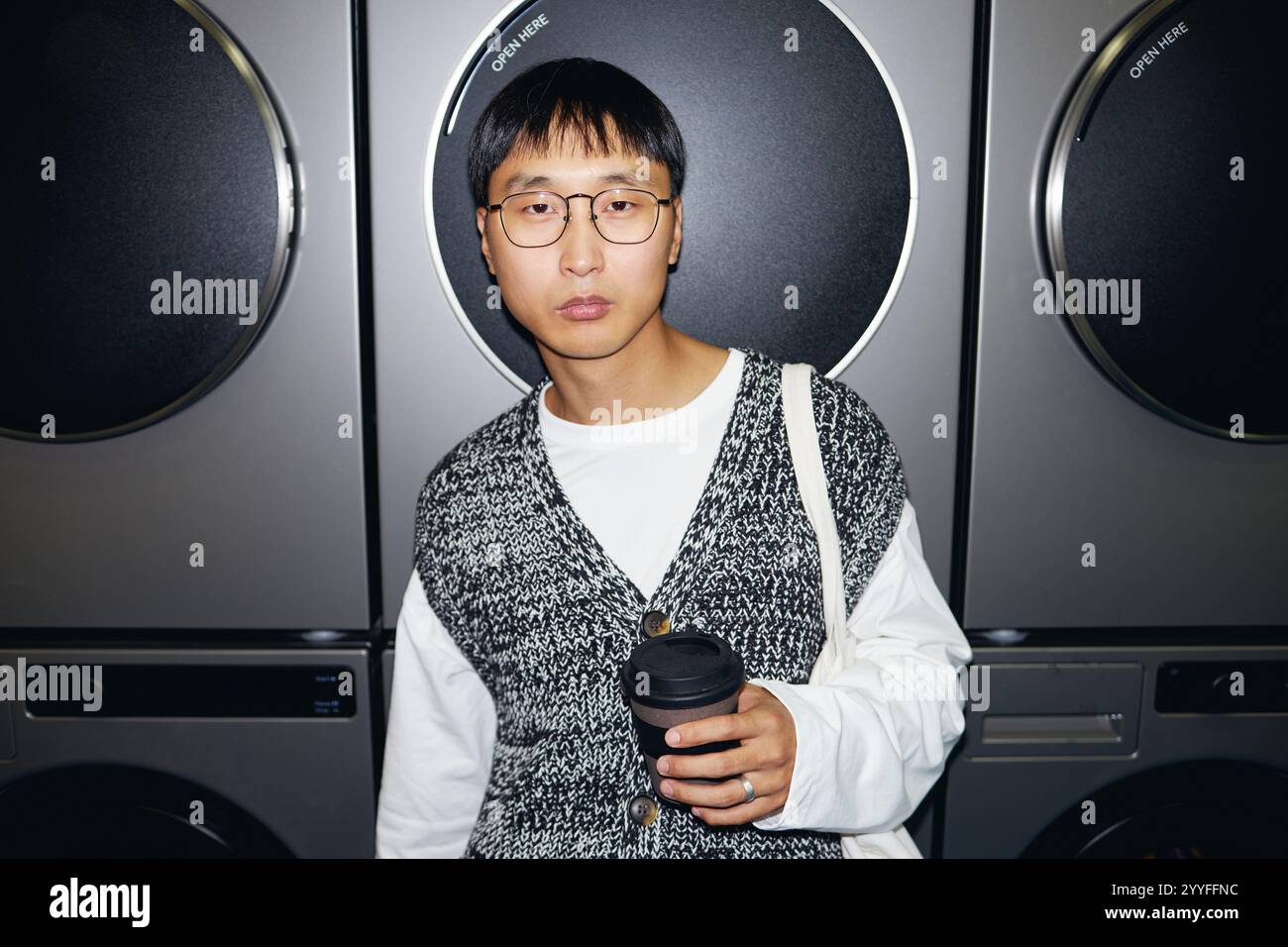 Portrait of modern Asian man with reusable cup in hand standing against ...