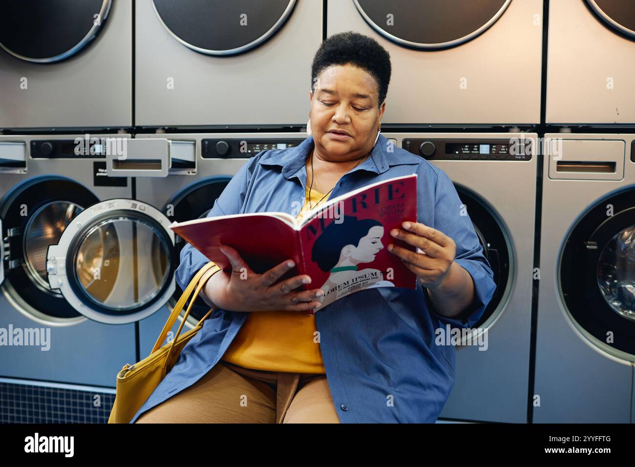 Medium shot of senior African American woman reading magazine while ...