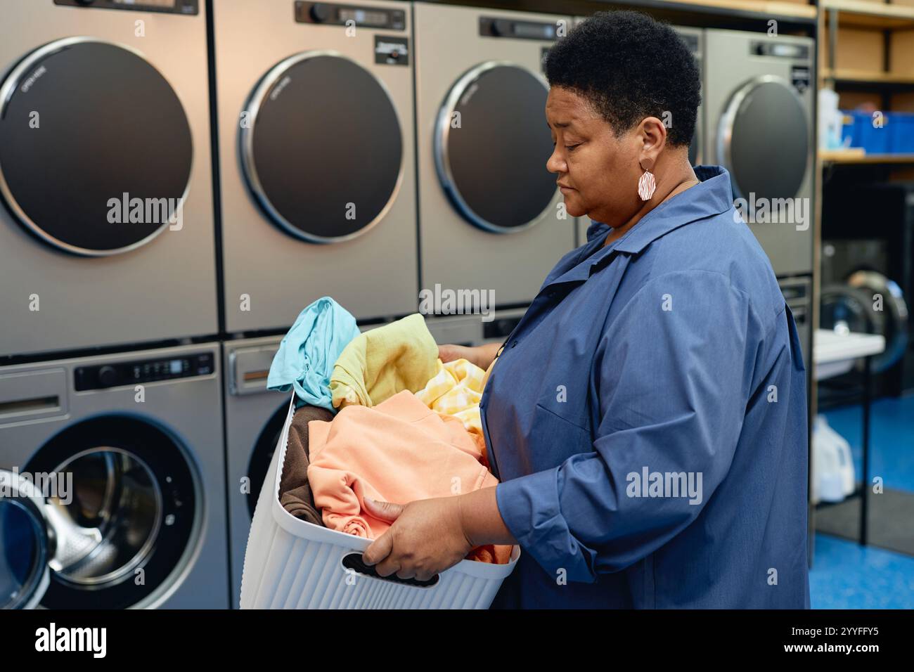 Side view of senior African American woman carrying basket of laundry ...