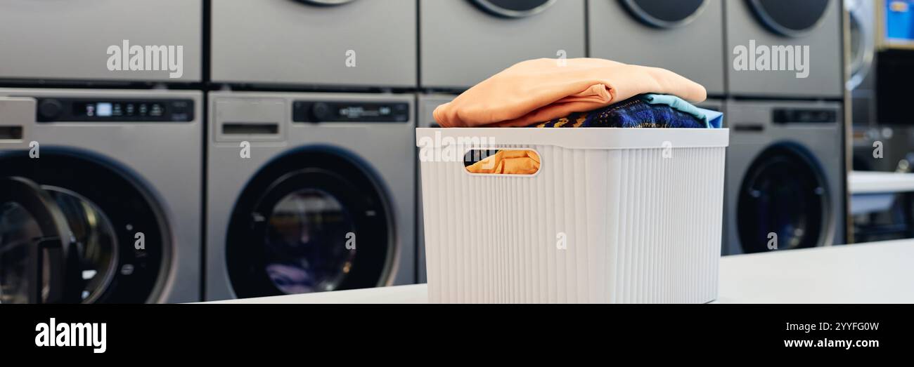 Website header shot of basket with clean and fresh clothes on folding table in self service ...