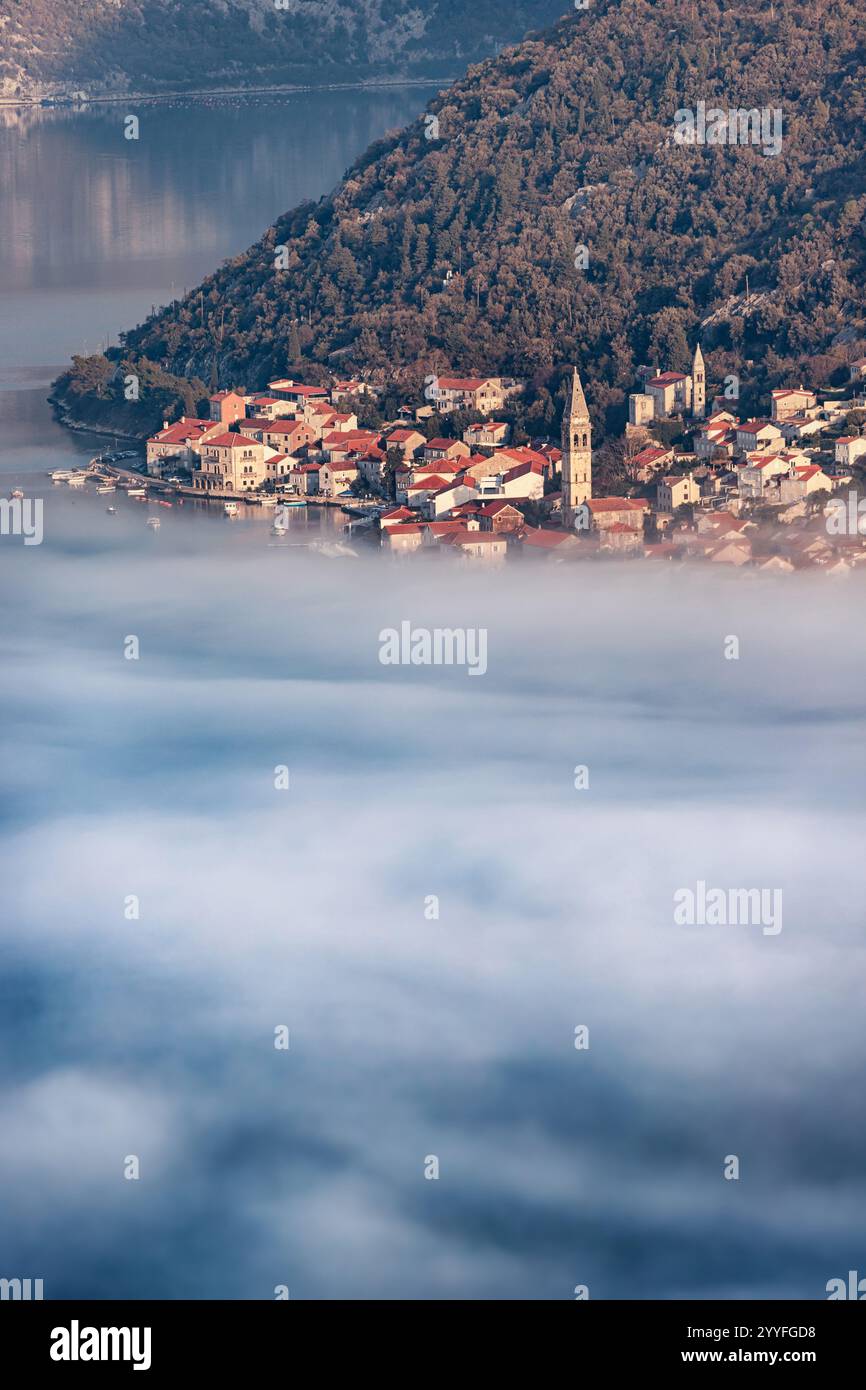 Scenic view of Perast village partially covered by fog at sunrise, with ...
