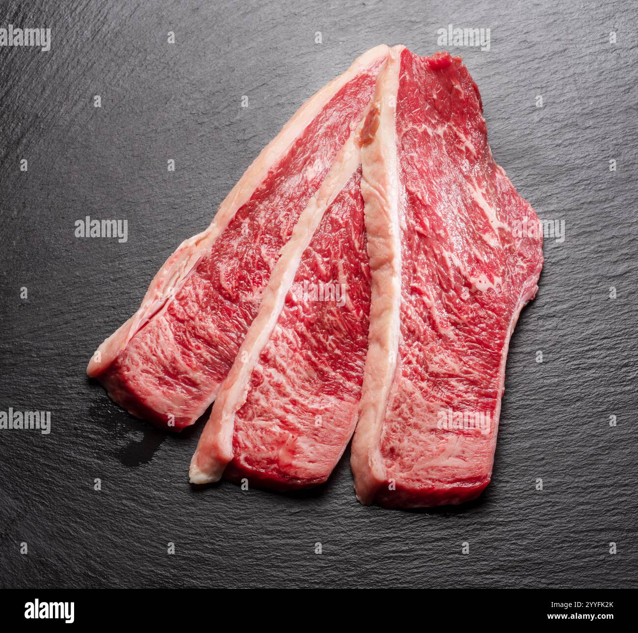 Sliced picanha beef on a gray stone serving board top view. Traditional ...