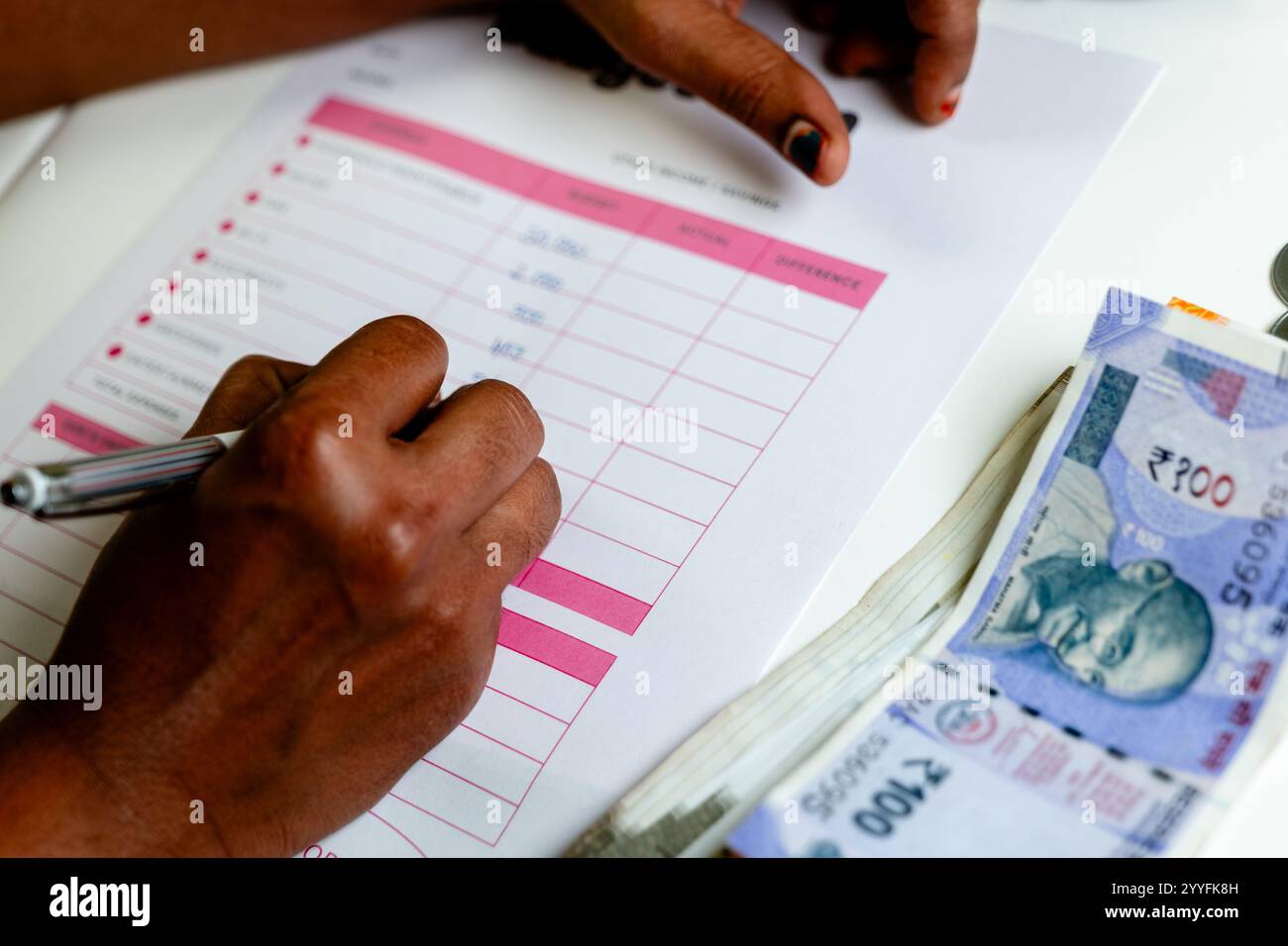 Hands calculating expenses and income with Indian Rupee banknotes ...