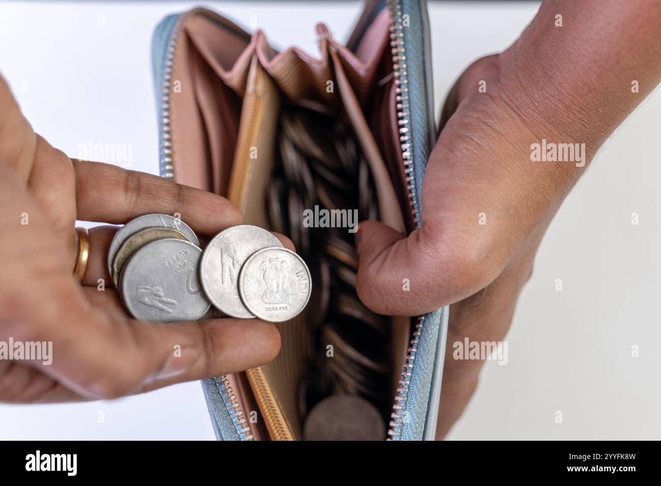 Hands holding Indian rupee coins with a wallet full of coins. Close up ...