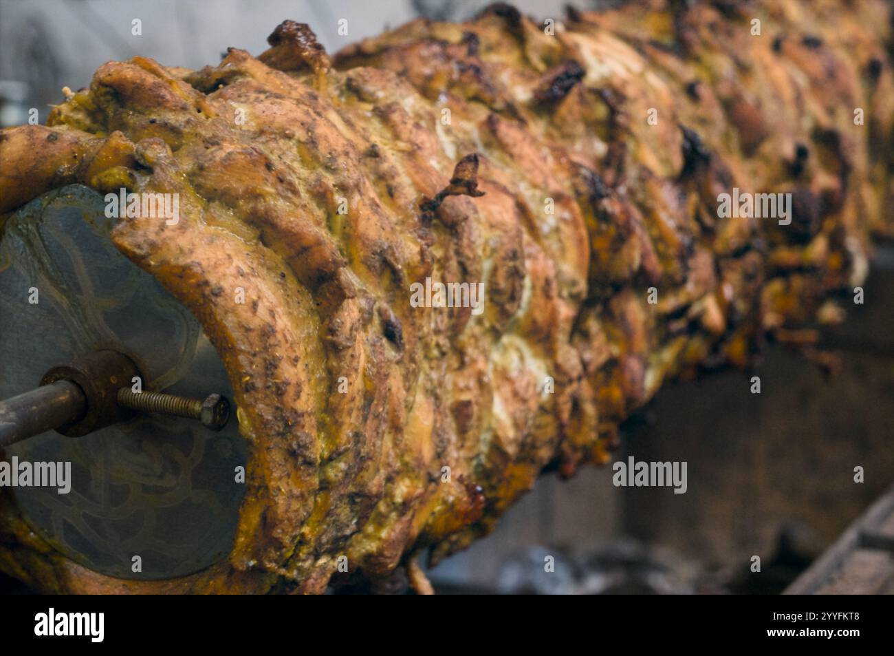 Rotating spit of seasoned chicken slowly cooking, ready to be shaved ...
