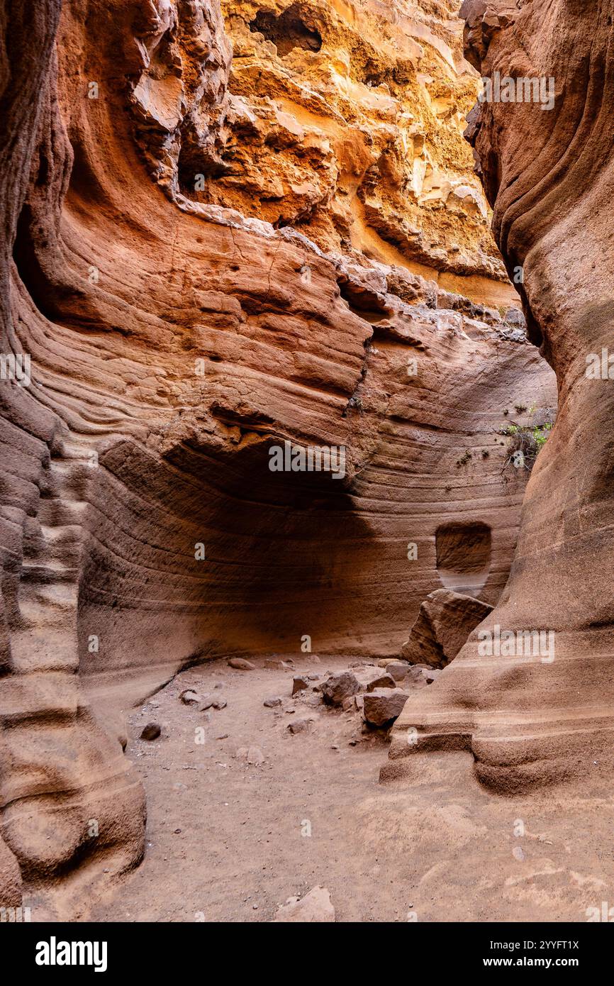 A narrow cave with a small opening. The cave is dark and the light is ...