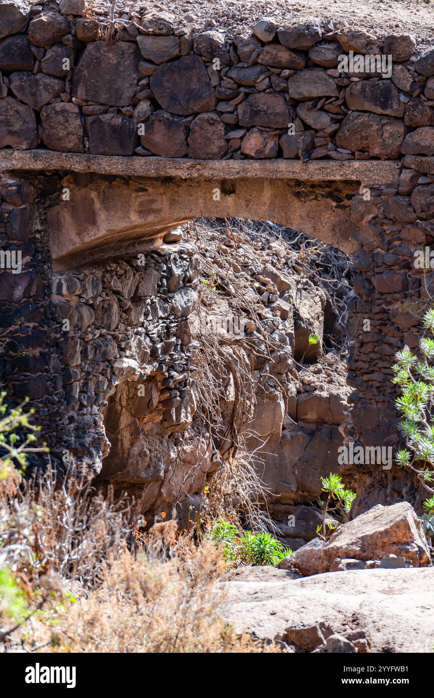 A stone archway with a stone wall on either side. The archway is open ...