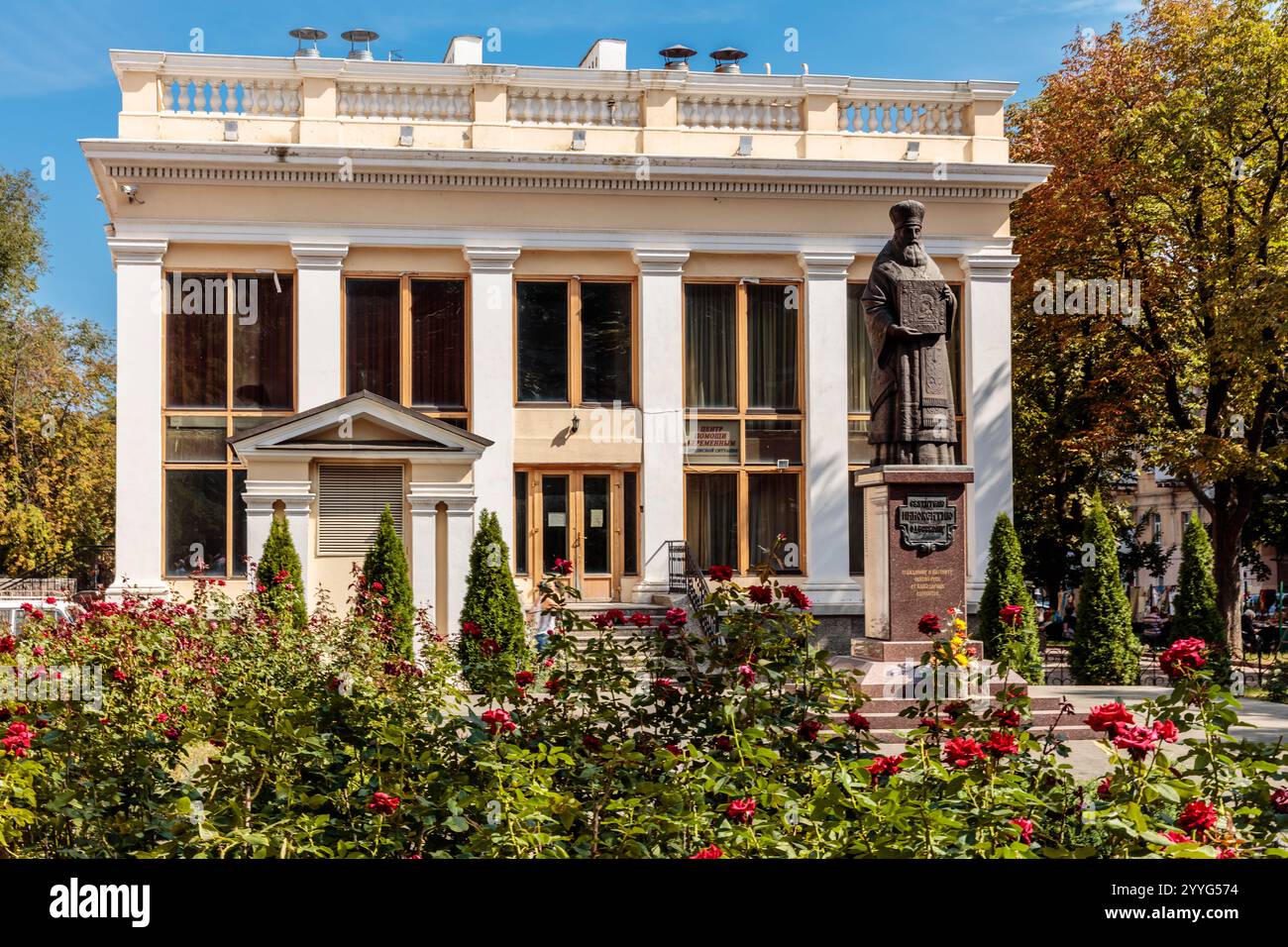 A large white building with a statue of a man in front of it. The ...