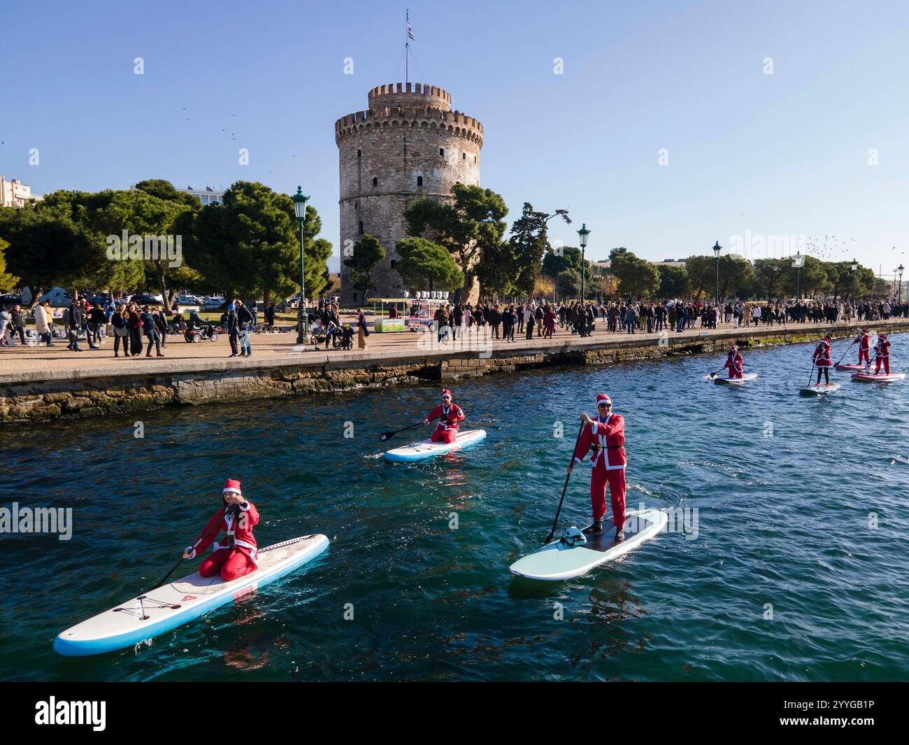 Participants wearing Santa Claus costumes, paddle during a Santa SUP ...
