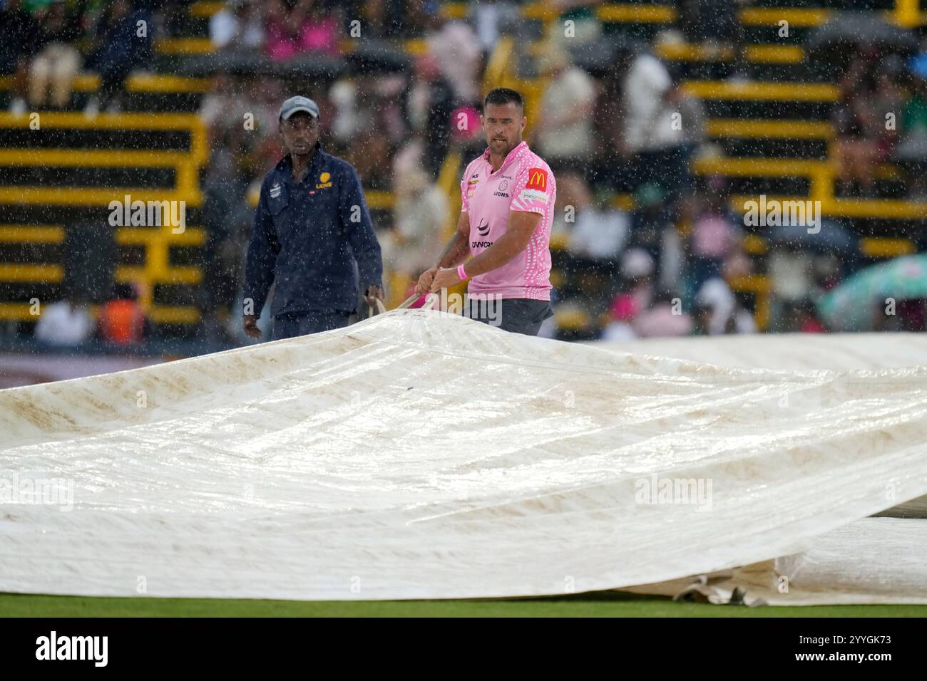Ground workers pull rain covers as play is delayed for the third ...