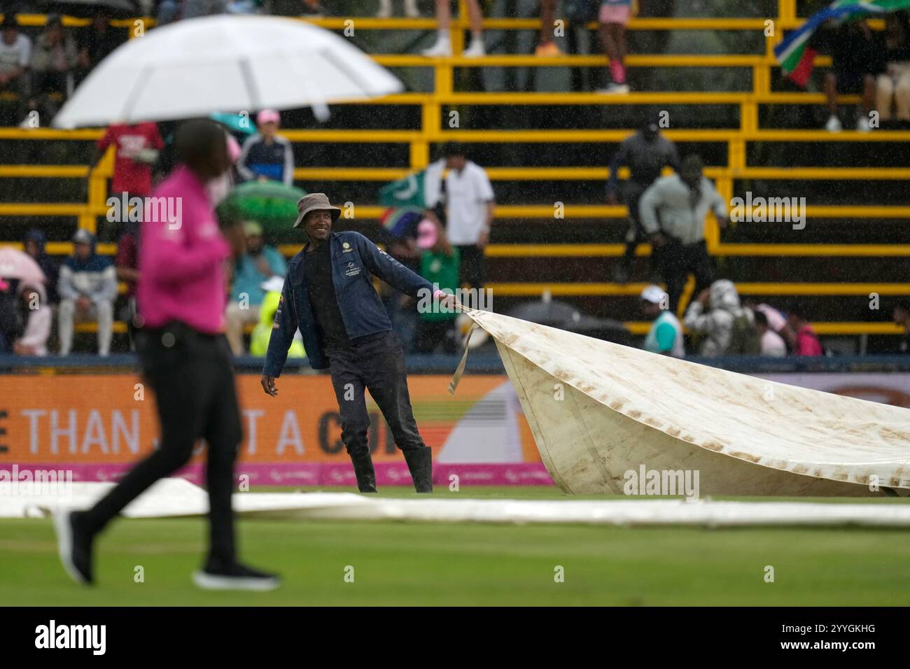Ground workers pull rain covers as play is delayed for the third ...