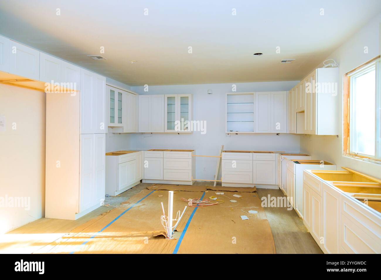Renovation work in modern kitchen with empty cabinets construction materials scattered during ...