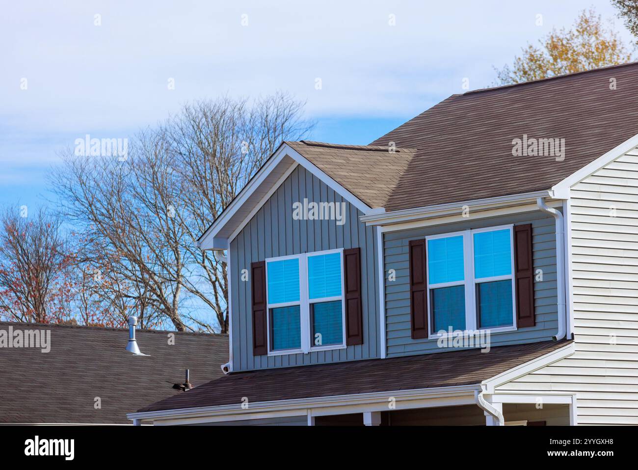 View of upper section of suburban house featuring grey siding, multiple ...