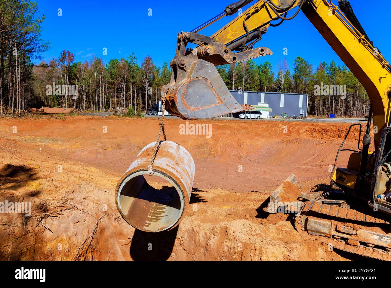 Large excavator is lifting concrete pipe to be placed at construction ...