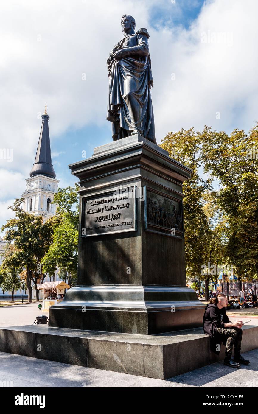 A statue of a man sits in front of a building. The statue is of a man ...
