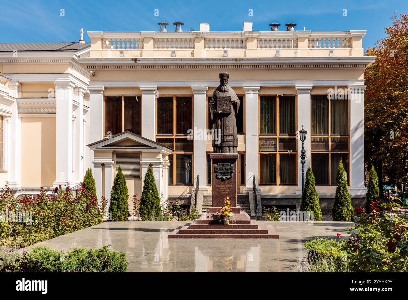 A statue of a man stands in front of a building. The statue is ...