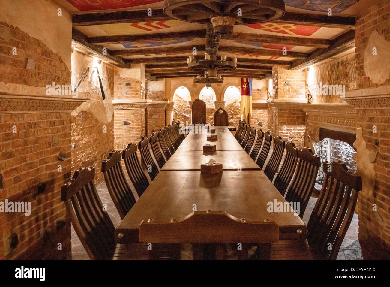 A long wooden table with many chairs and a flag on the wall. Scene is ...