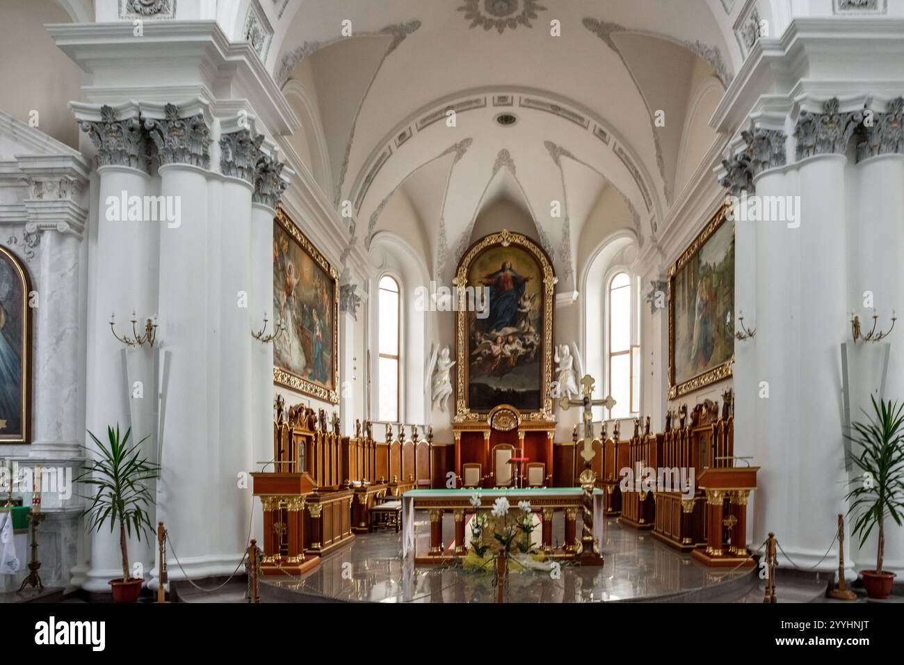 The interior of a church is very large and very white. There are many ...