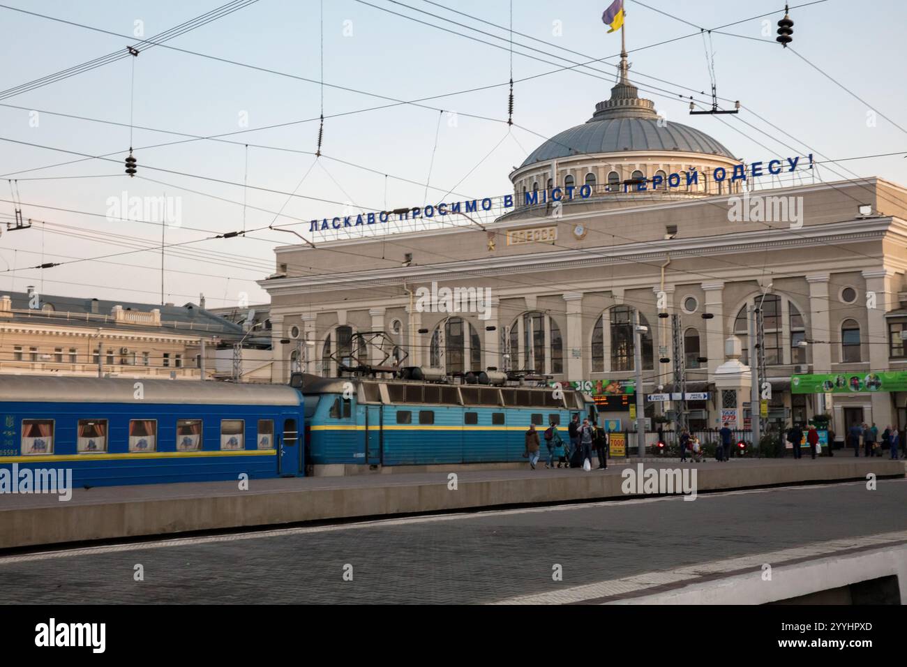A train is pulling into a station with a large building in the ...