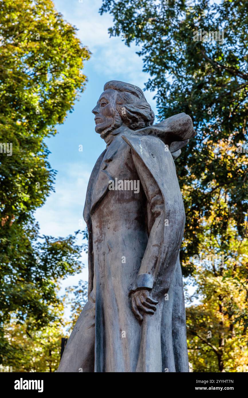 A statue of a man wearing a coat and hat. The statue is made of bronze ...