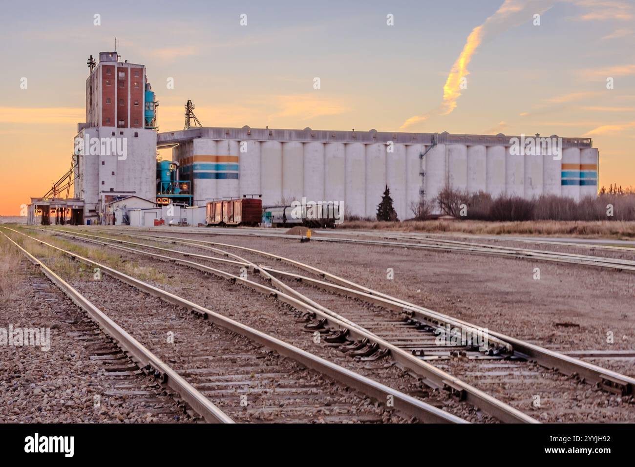 A train track with a large grain silo in the background. The silo is ...