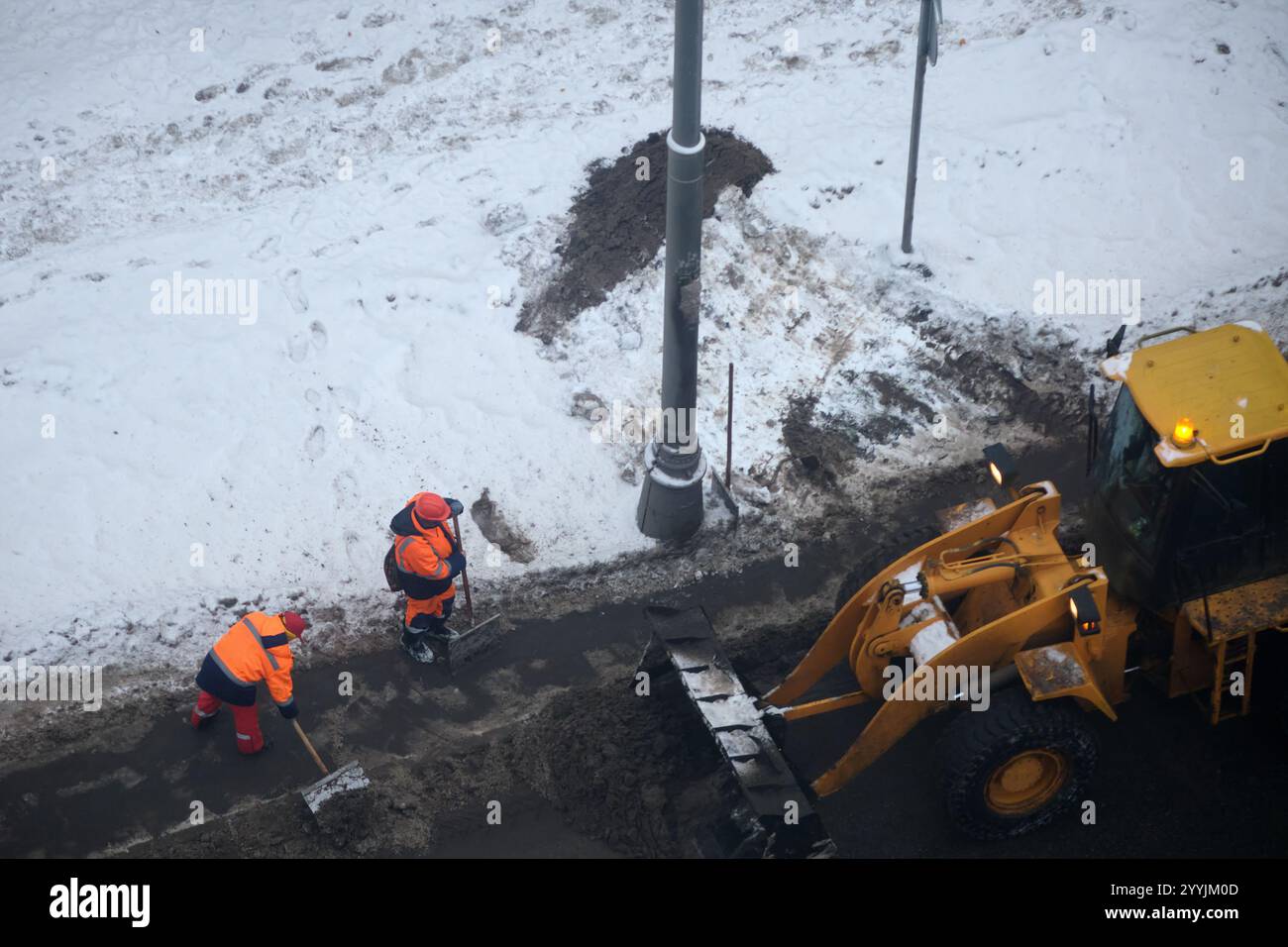 Workers clearing snow near construction site with loader and shovels ...