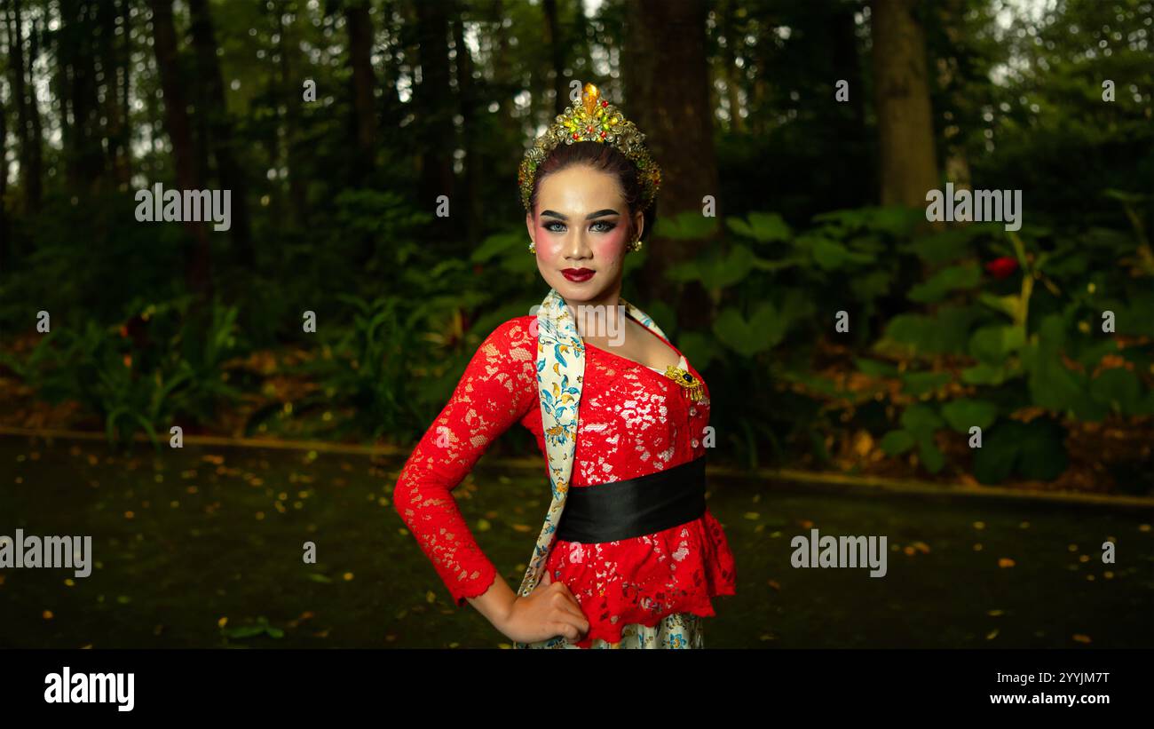 A traditional dancer called ronggeng dazzlingly stands in the forest with great elegance and ...