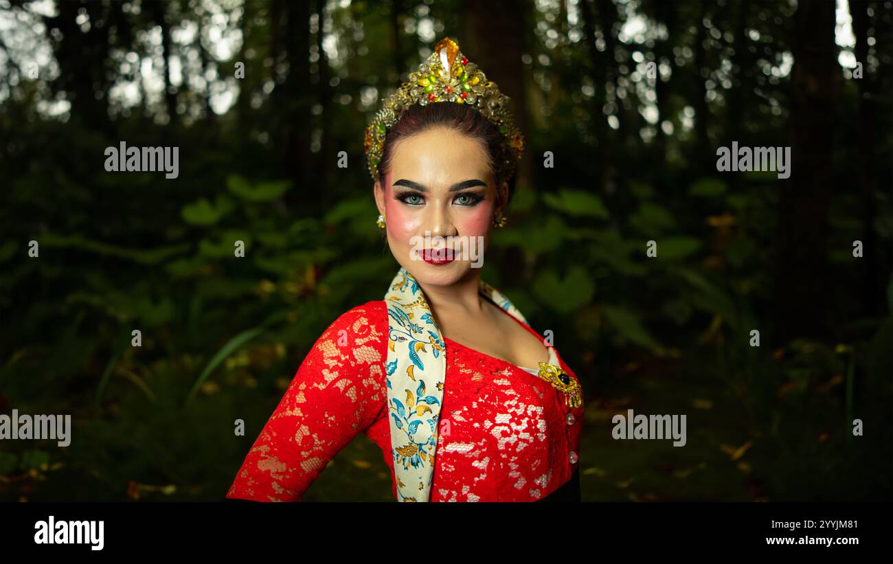 A traditional dancer called ronggeng dazzlingly stands in the forest with great elegance and ...