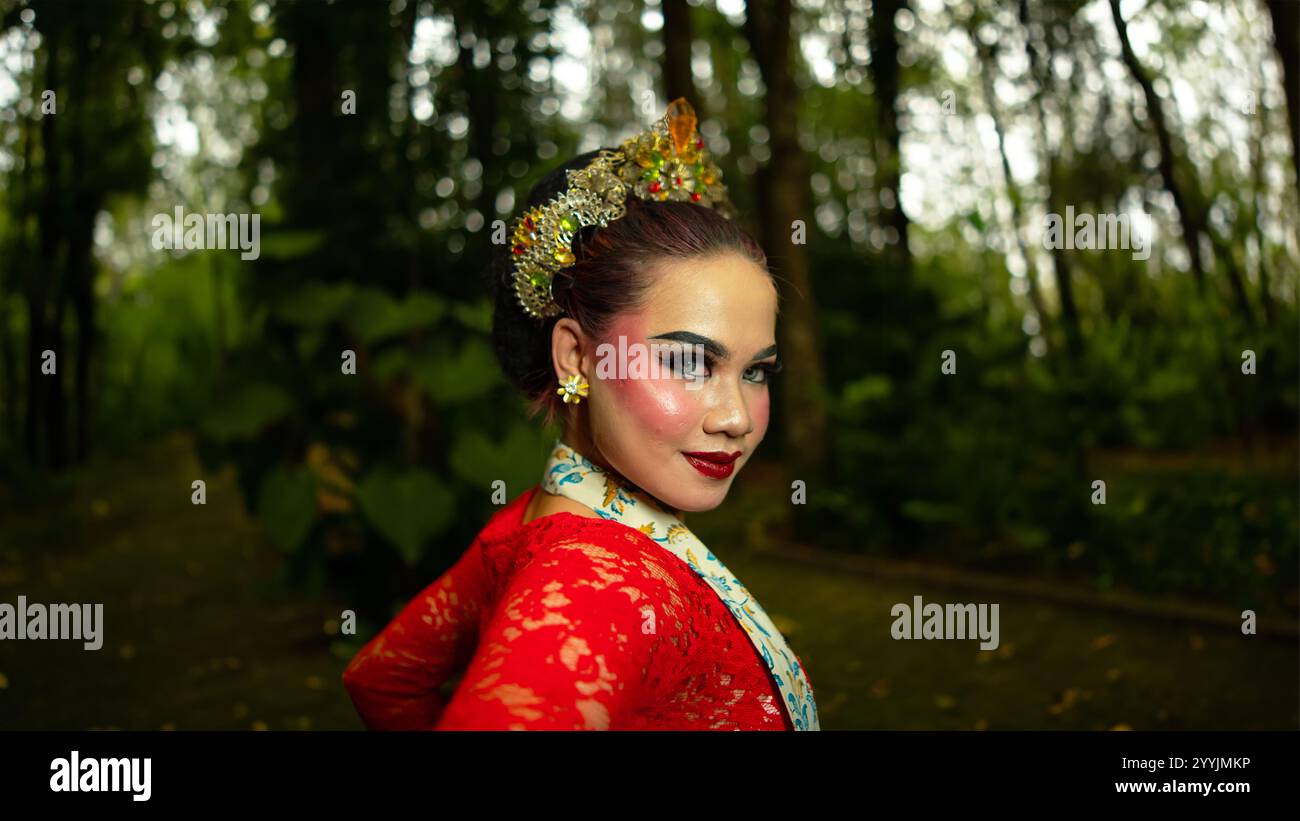 A Javanese dancer wears an elegant red costume and emphasizes the ...