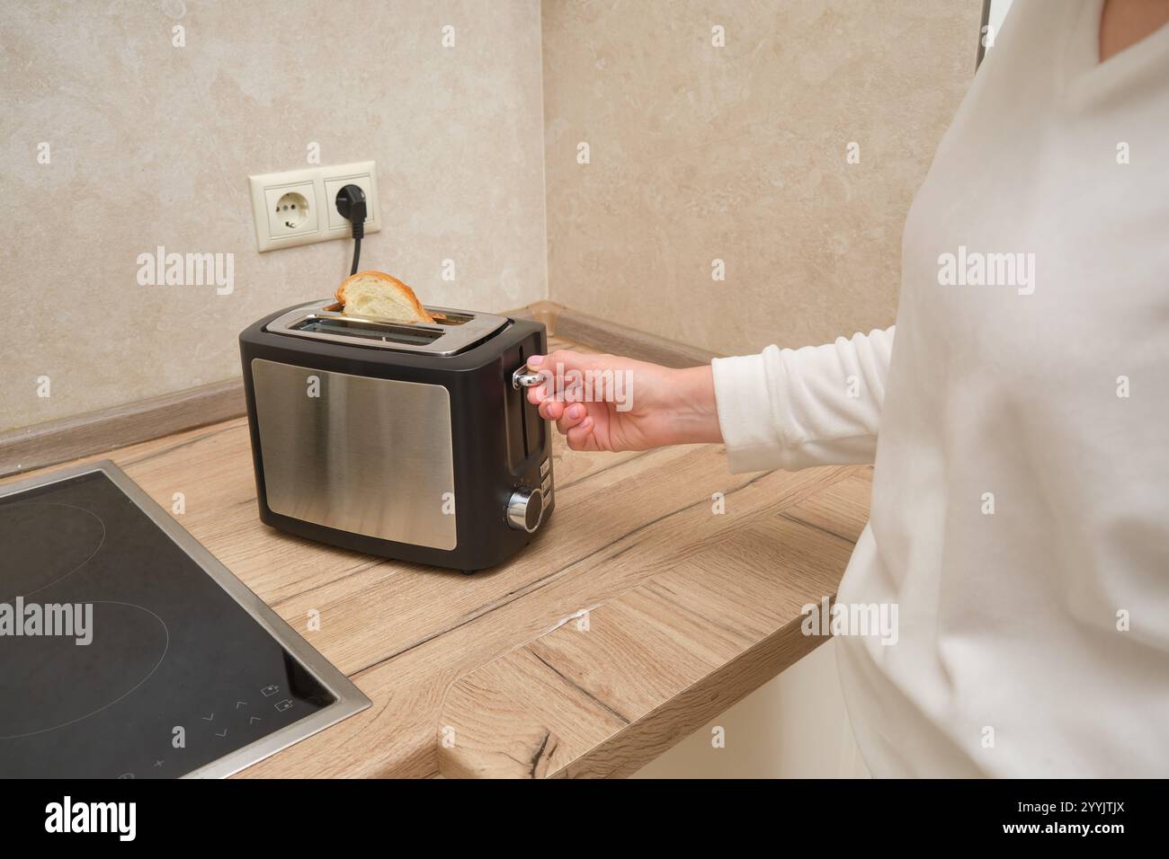 Person using black and stainless steel toaster with slice of bread in ...