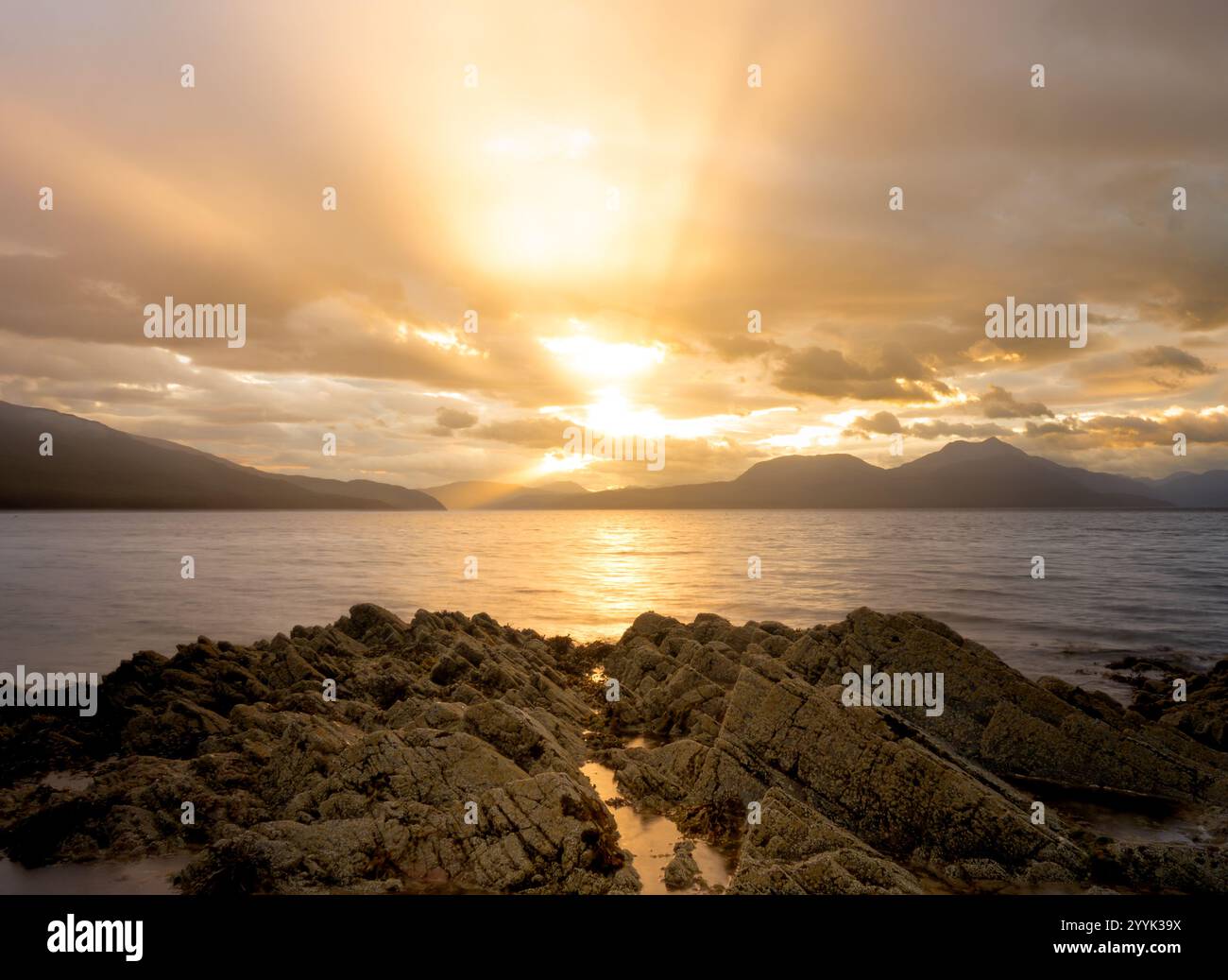 Sunrise over water by a mountain and sea landscape with golden sun ...