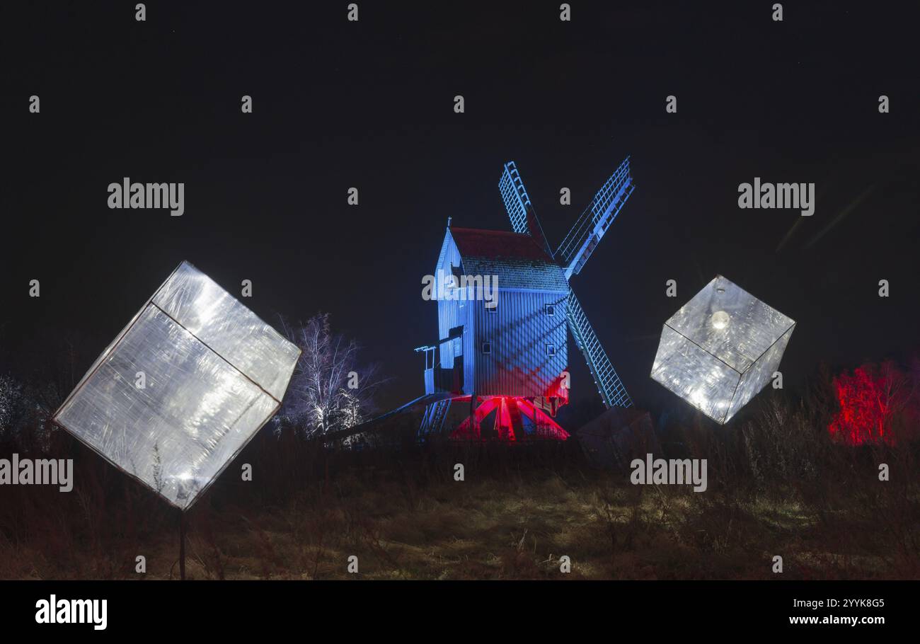 Illuminated windmill with cubes in the foreground in a nocturnal ...