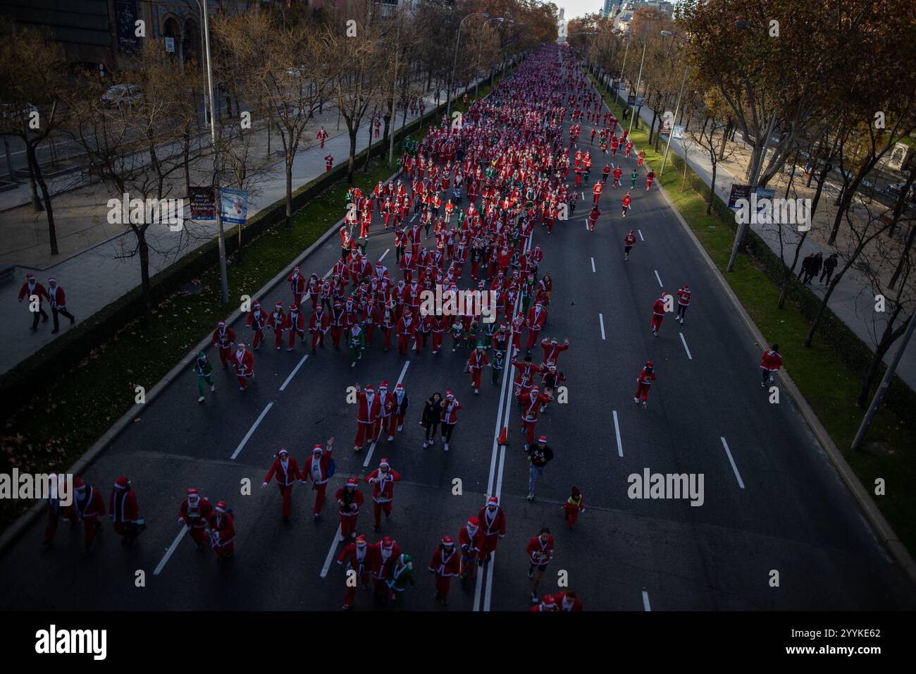 Hundreds of runners dressed as Santa Claus run through a street in the ...