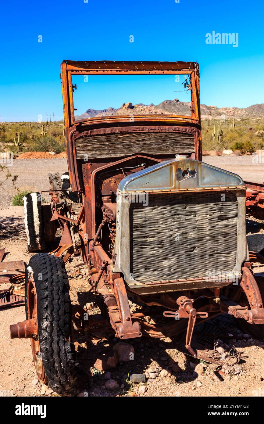 An old, rusted truck is parked in a desert. The truck is covered in ...