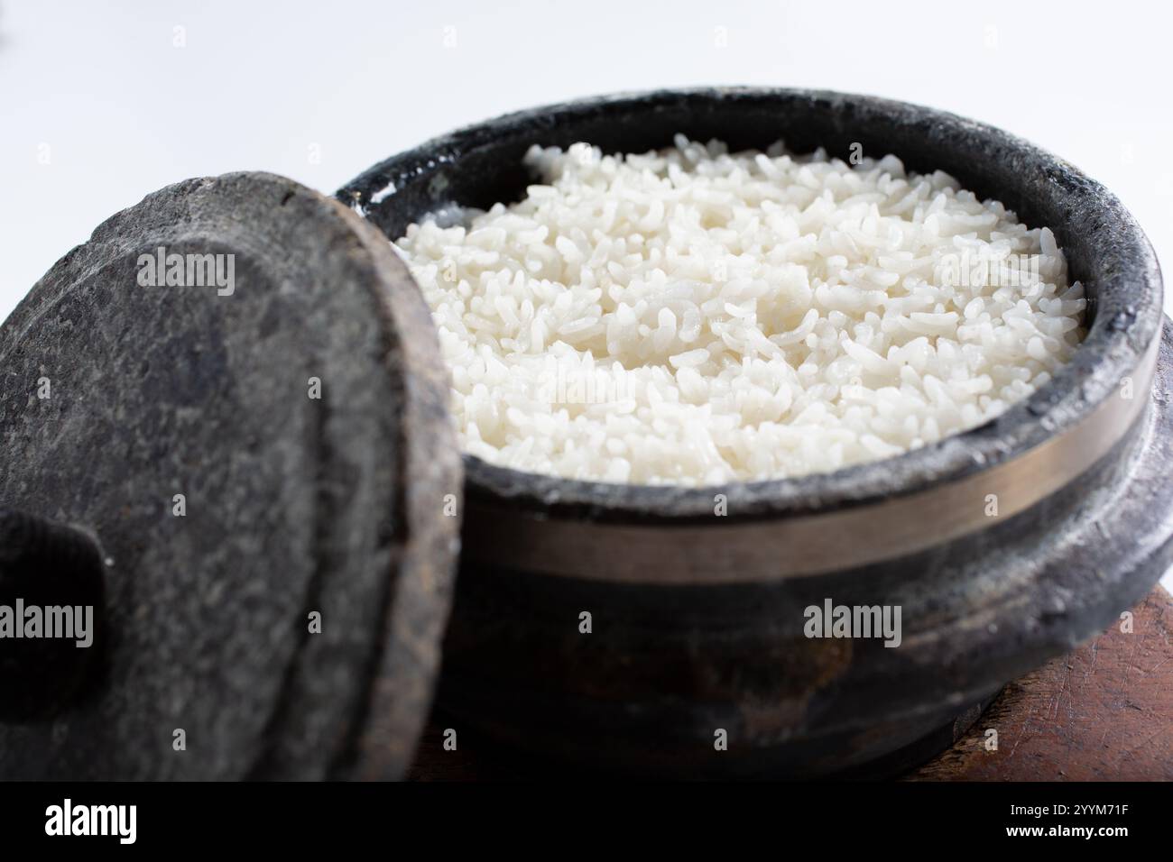 A view of white rice cooked inside a Korean stone pot. The stone lid is ...