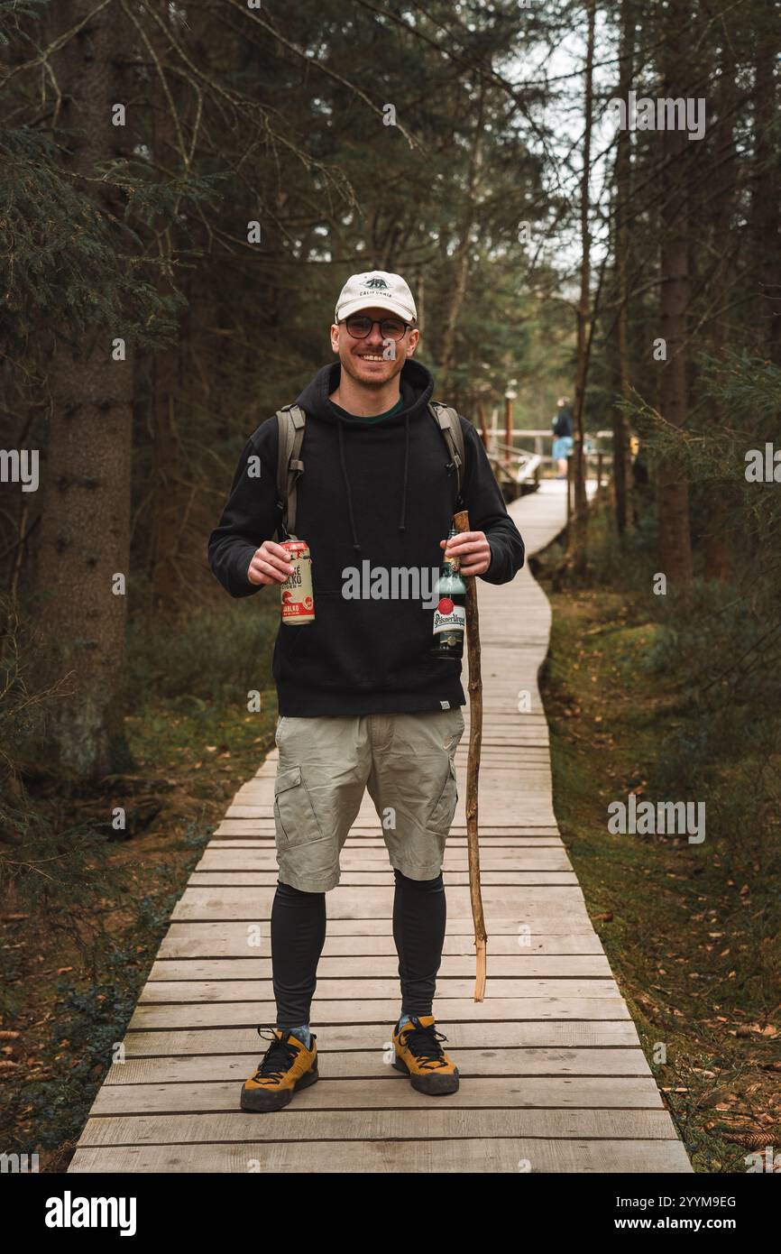 A man leisurely walking down a rustic wooden walkway while holding a ...