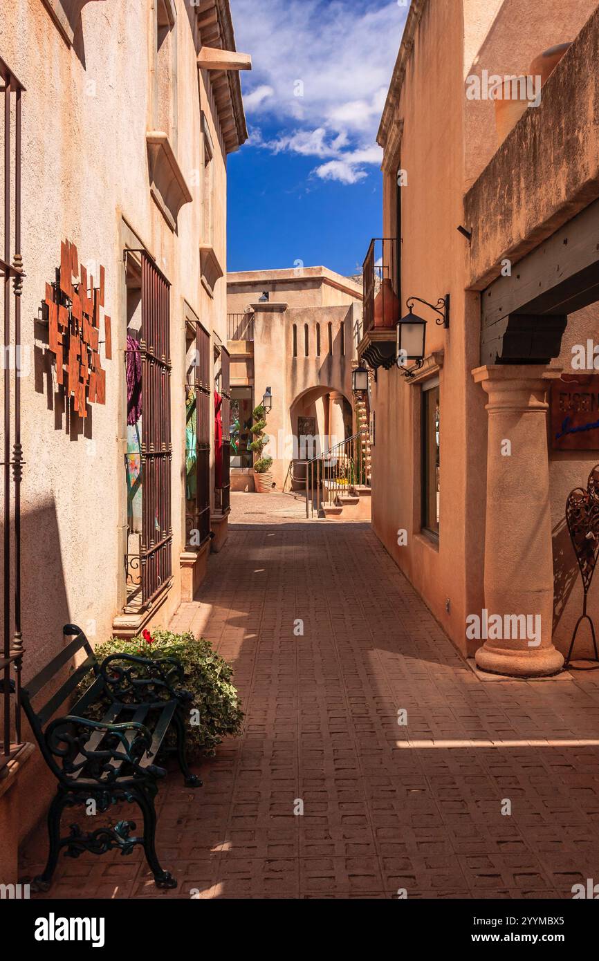 A narrow alleyway with a bench and a potted plant. The bench is empty ...