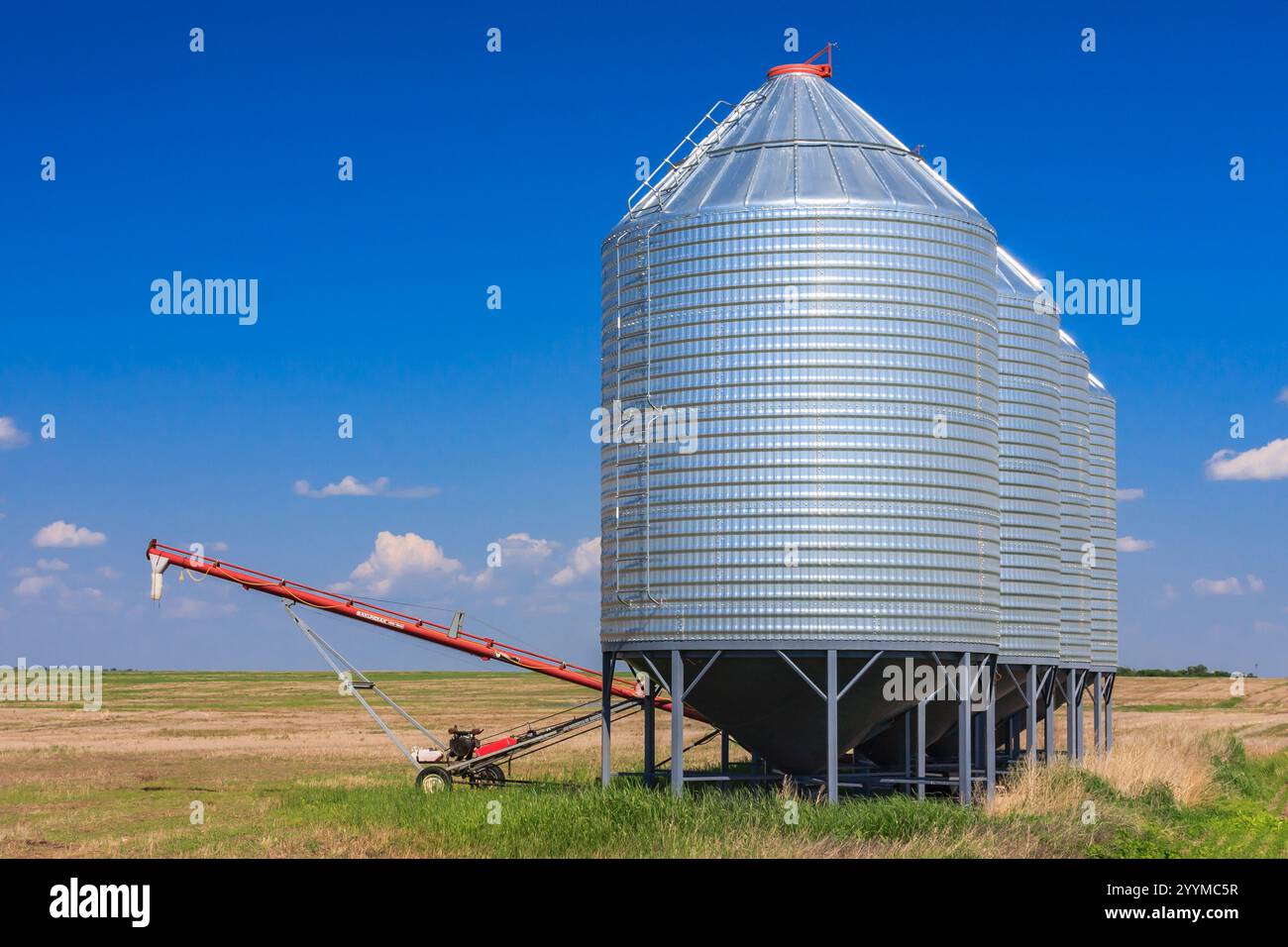 A large silo with a red crane next to it. The silo is empty and the sky ...