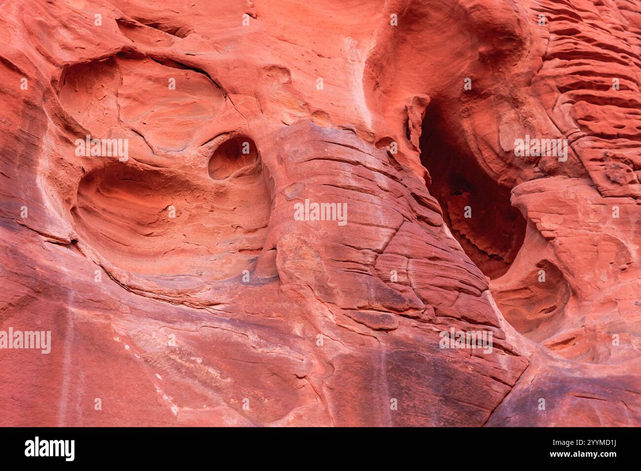 A large rock with a hole in it, surrounded by a red and brown color ...