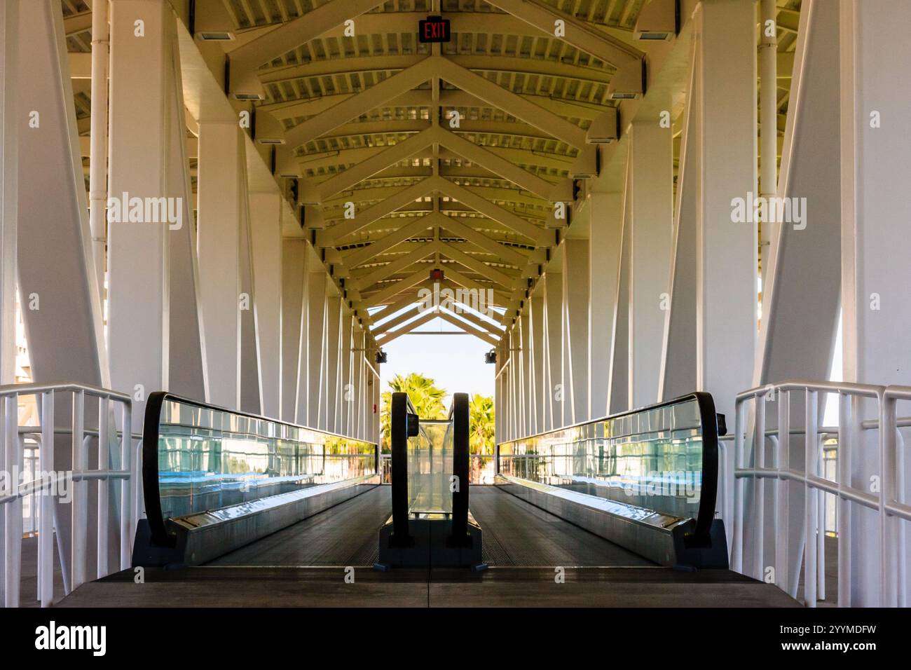A long, empty, white building with escalators. The escalators are not ...