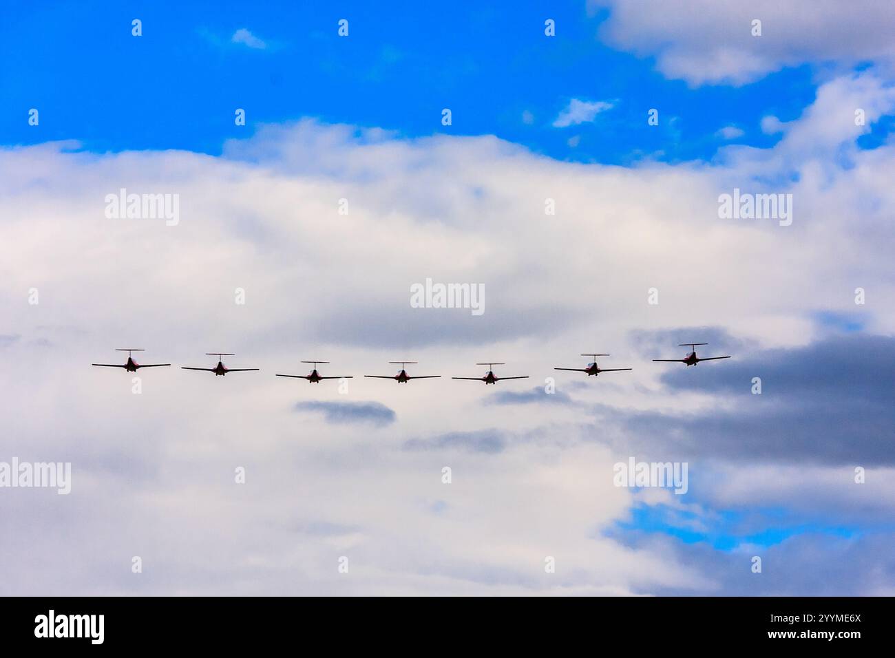 A group of planes fly in formation in the sky. The clouds are white and ...