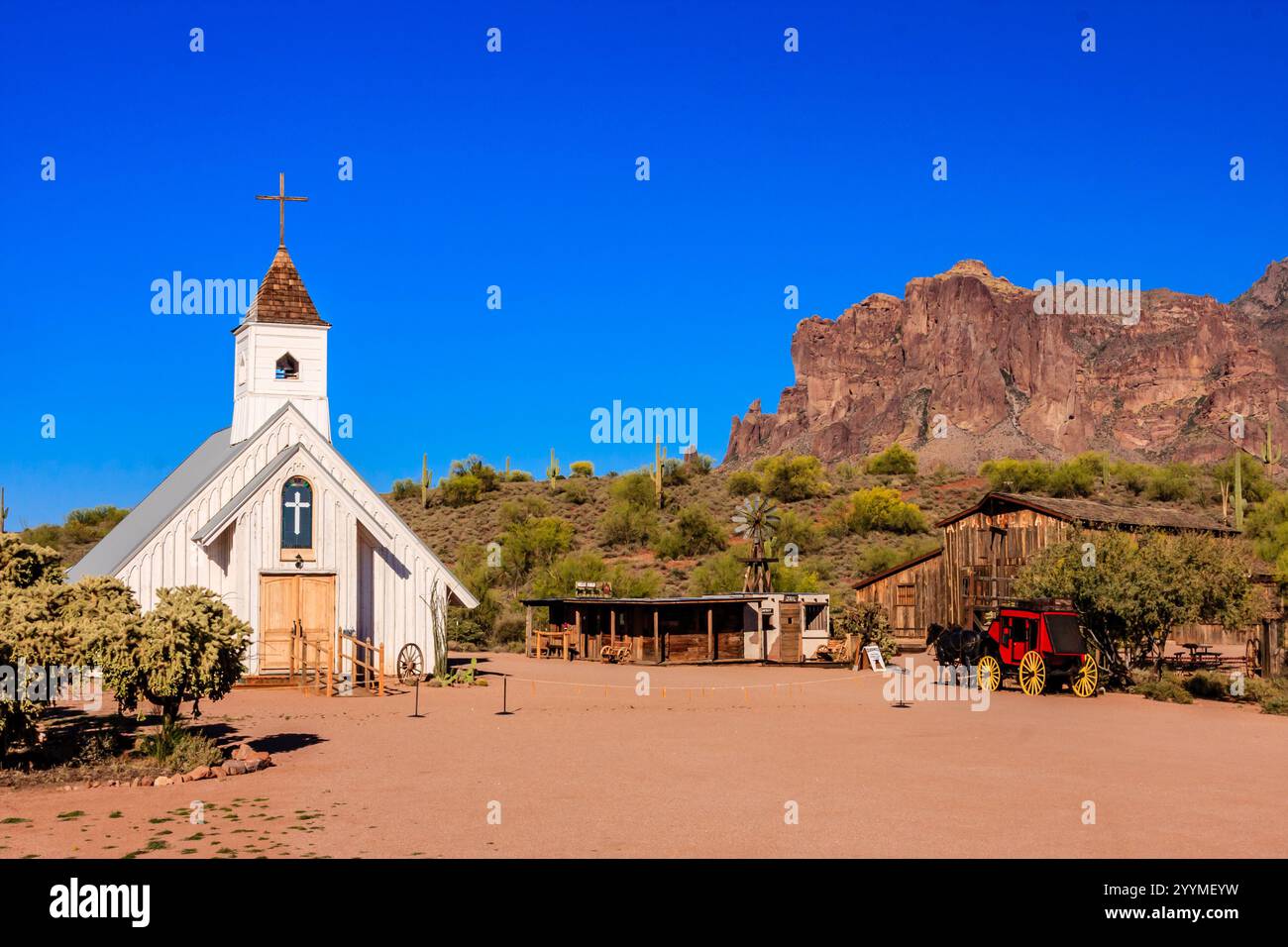 A small church sits in front of a large mountain. The church is white ...