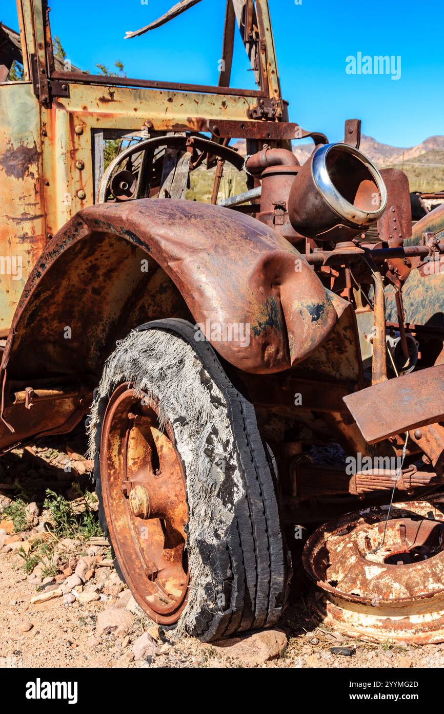 An old, rusted truck with a broken front tire. The tire is black and ...