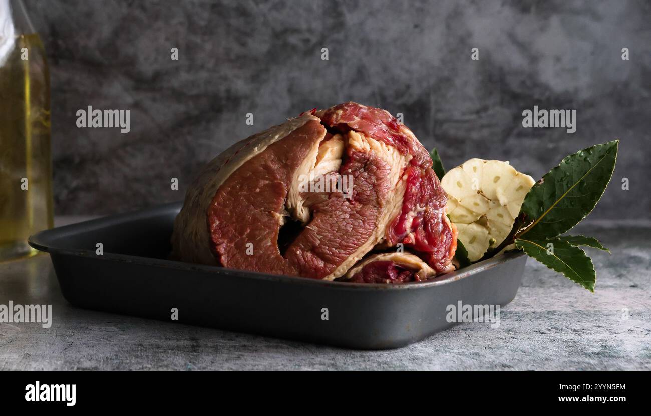 A creative tray of raw beef with cross cut whole garlic bulb and Bay ...