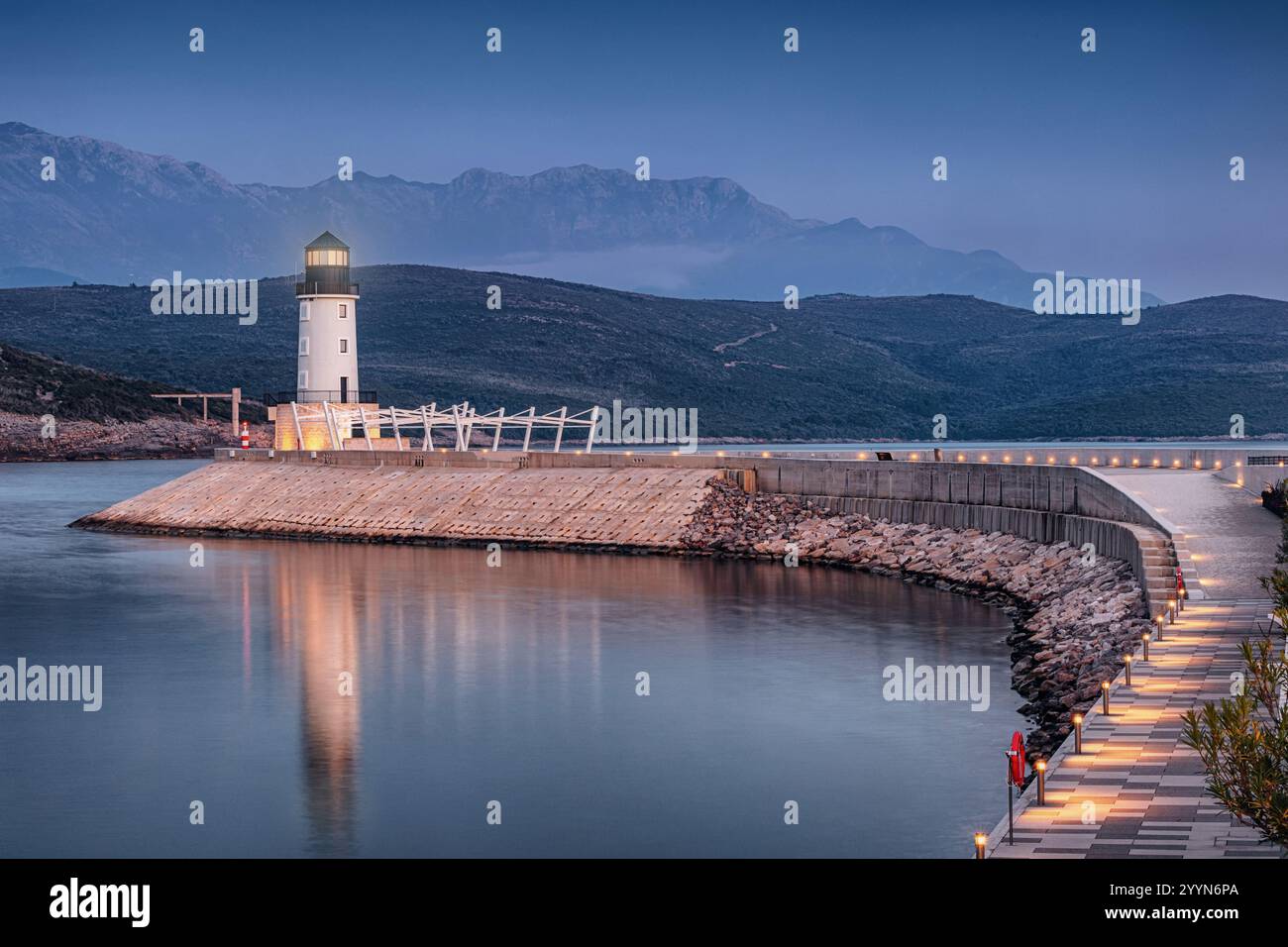 Modern lighthouse illuminating the tranquil waters of a bay at dusk ...