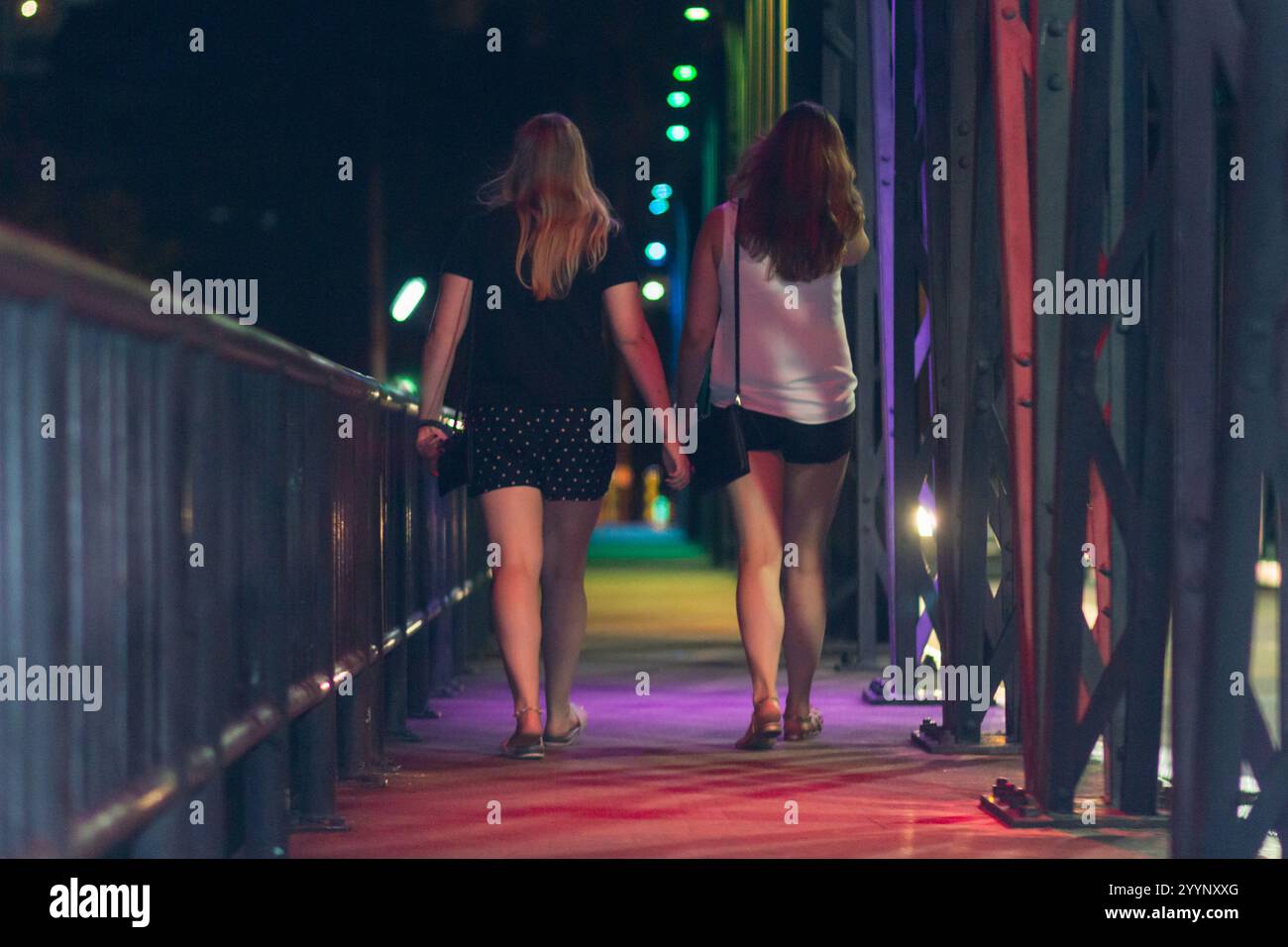 The background of the bridge over the river at night, two girls are ...